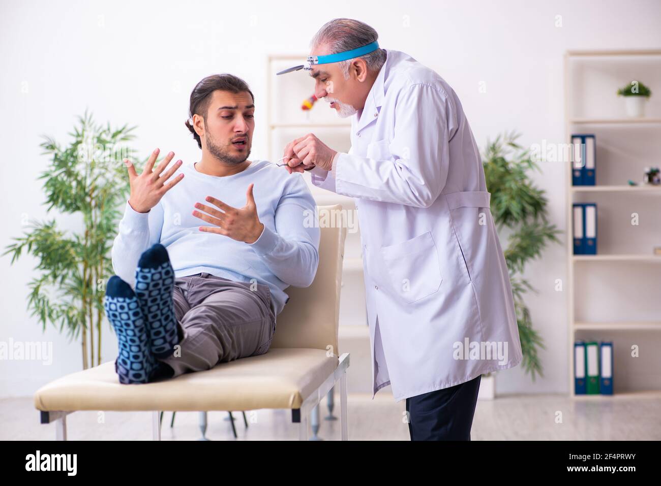 Sick man visiting old doctor otolaryngologist Stock Photo - Alamy