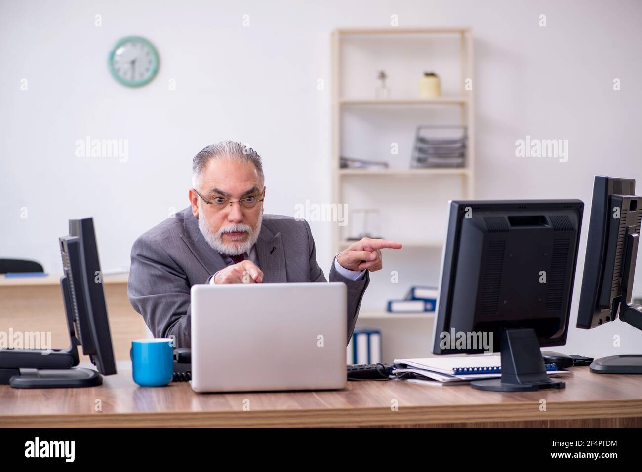 Old boss sitting at desktop in the office Stock Photo - Alamy