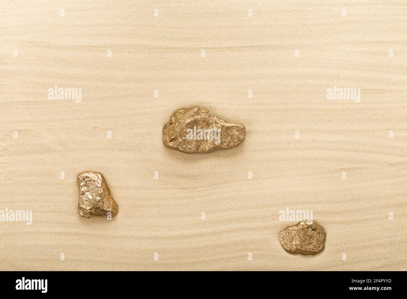 Heap of golden stones on waved sand. Photo can be used as a whole ...