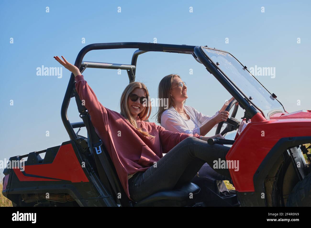 girls enjoying a beautiful sunny day while driving an off-road car ...