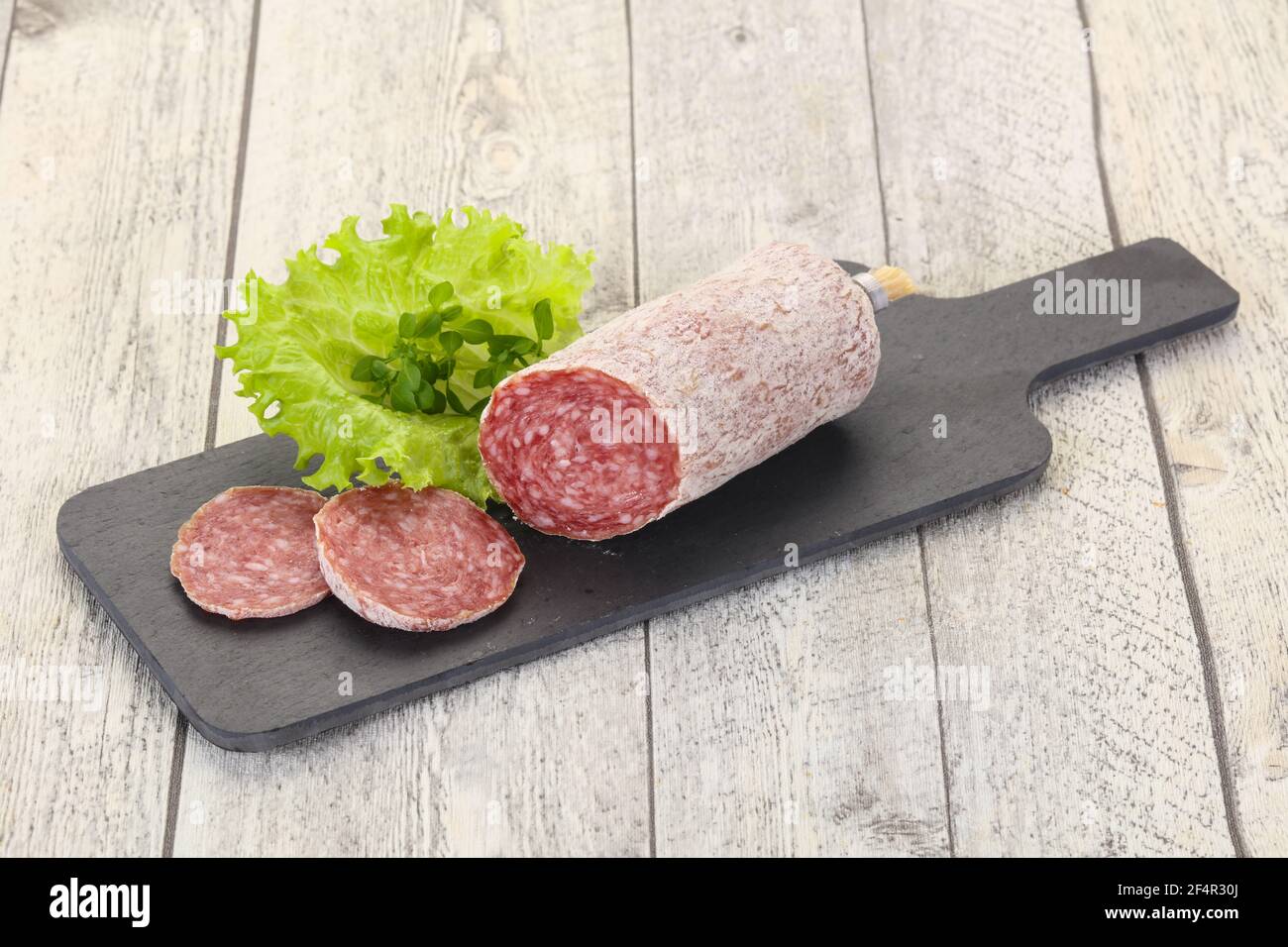 Italian dry Saliami pork sausage served salad leaves Stock Photo - Alamy