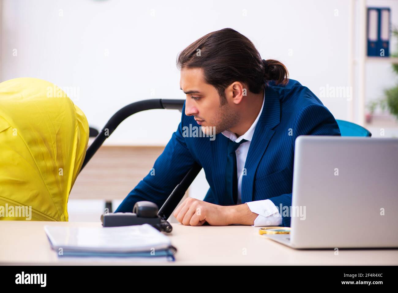 Young employee looking after kid at workplace Stock Photo - Alamy