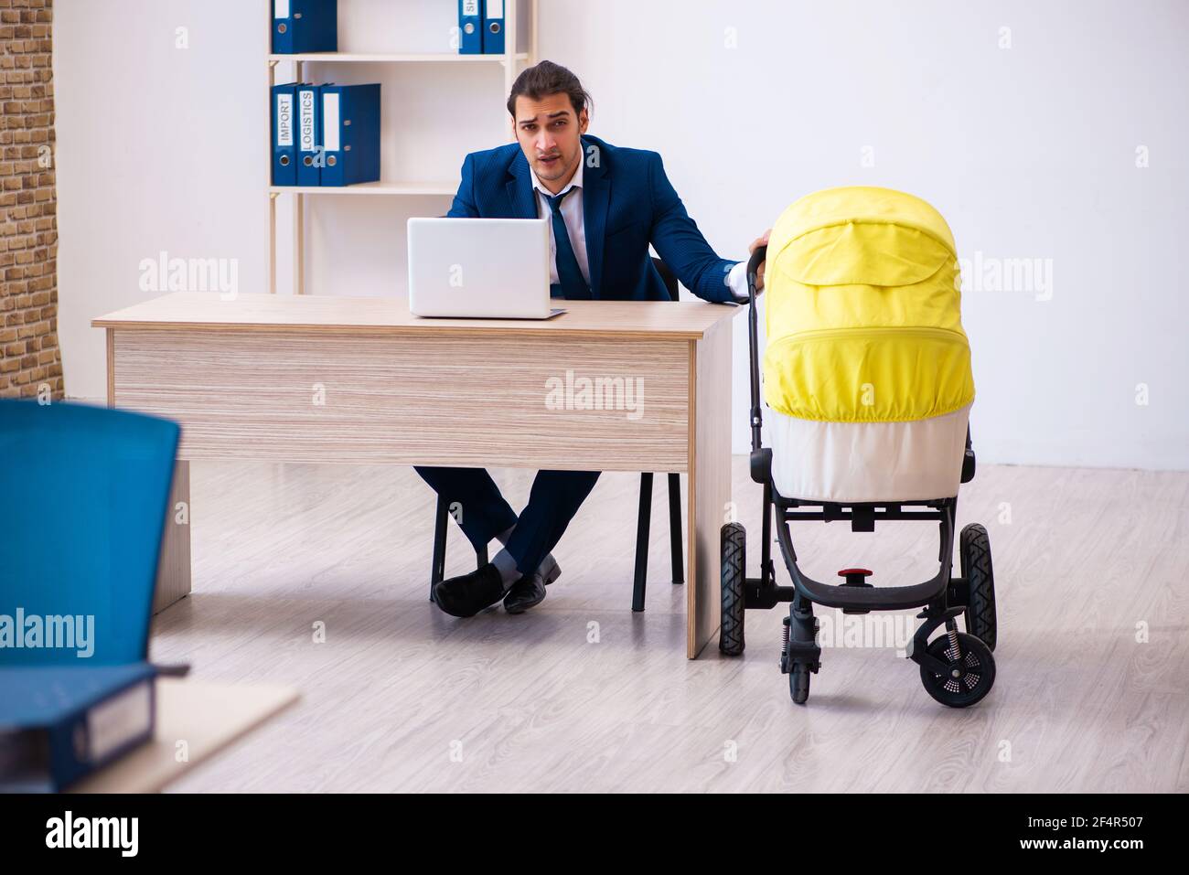 Young employee looking after kid at workplace Stock Photo - Alamy