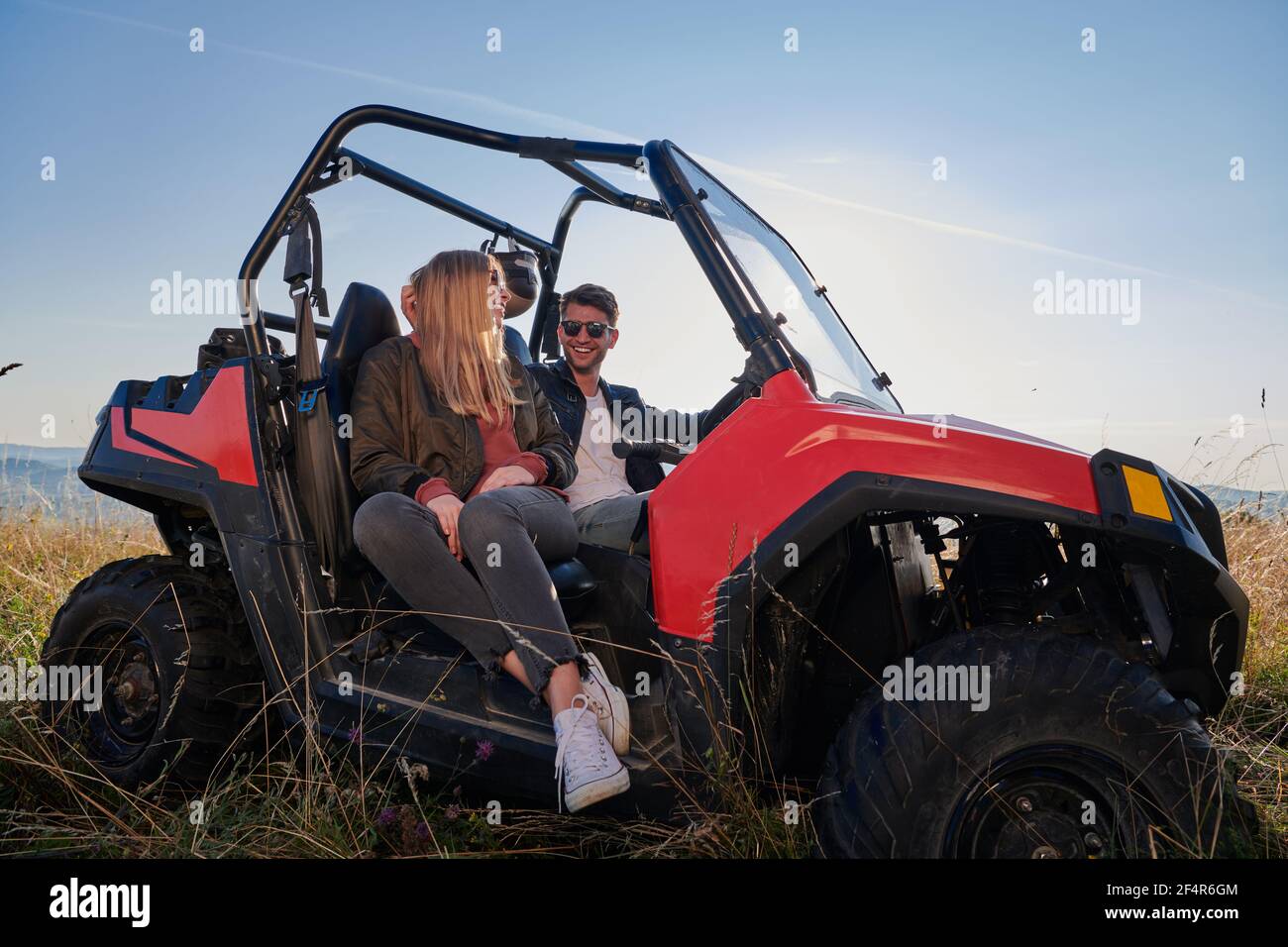couple enjoying beautiful sunny day while driving a off road buggy ...