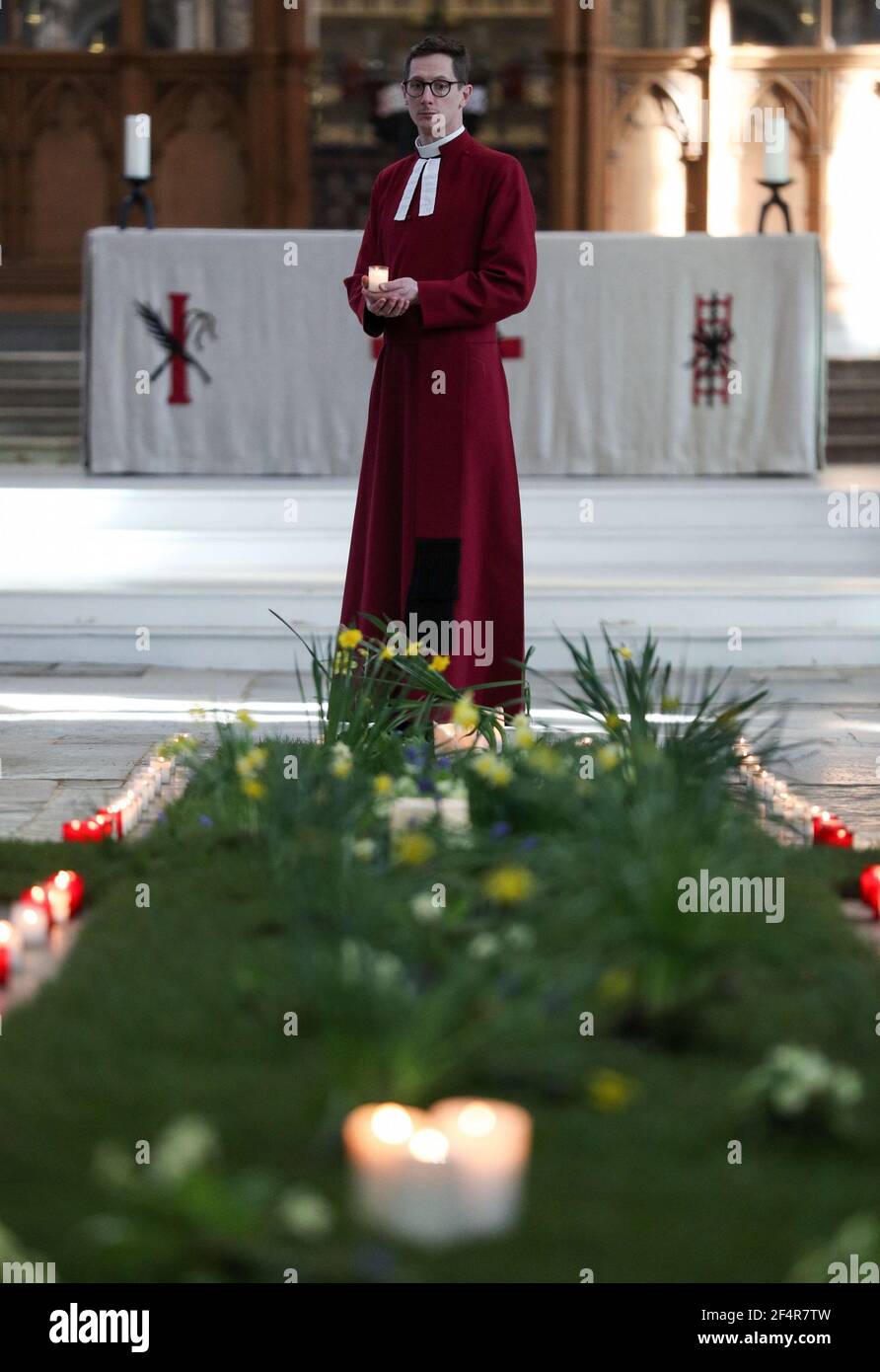 Reverend Canon Andrew Trenier holds a candle next to a green meadow ...