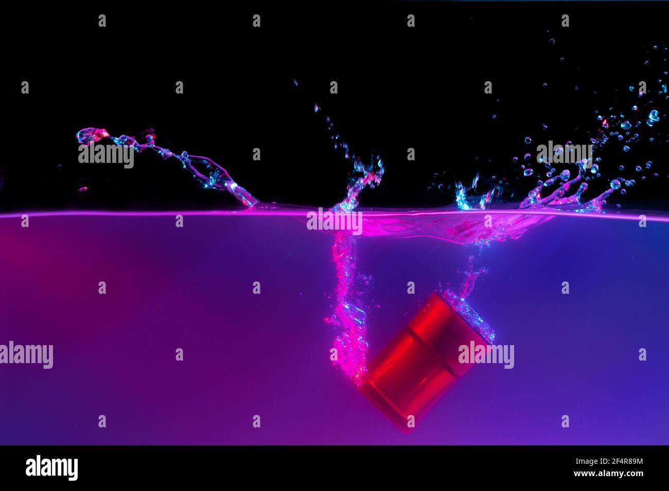 Skincare product bottle falling into water against black background in ...