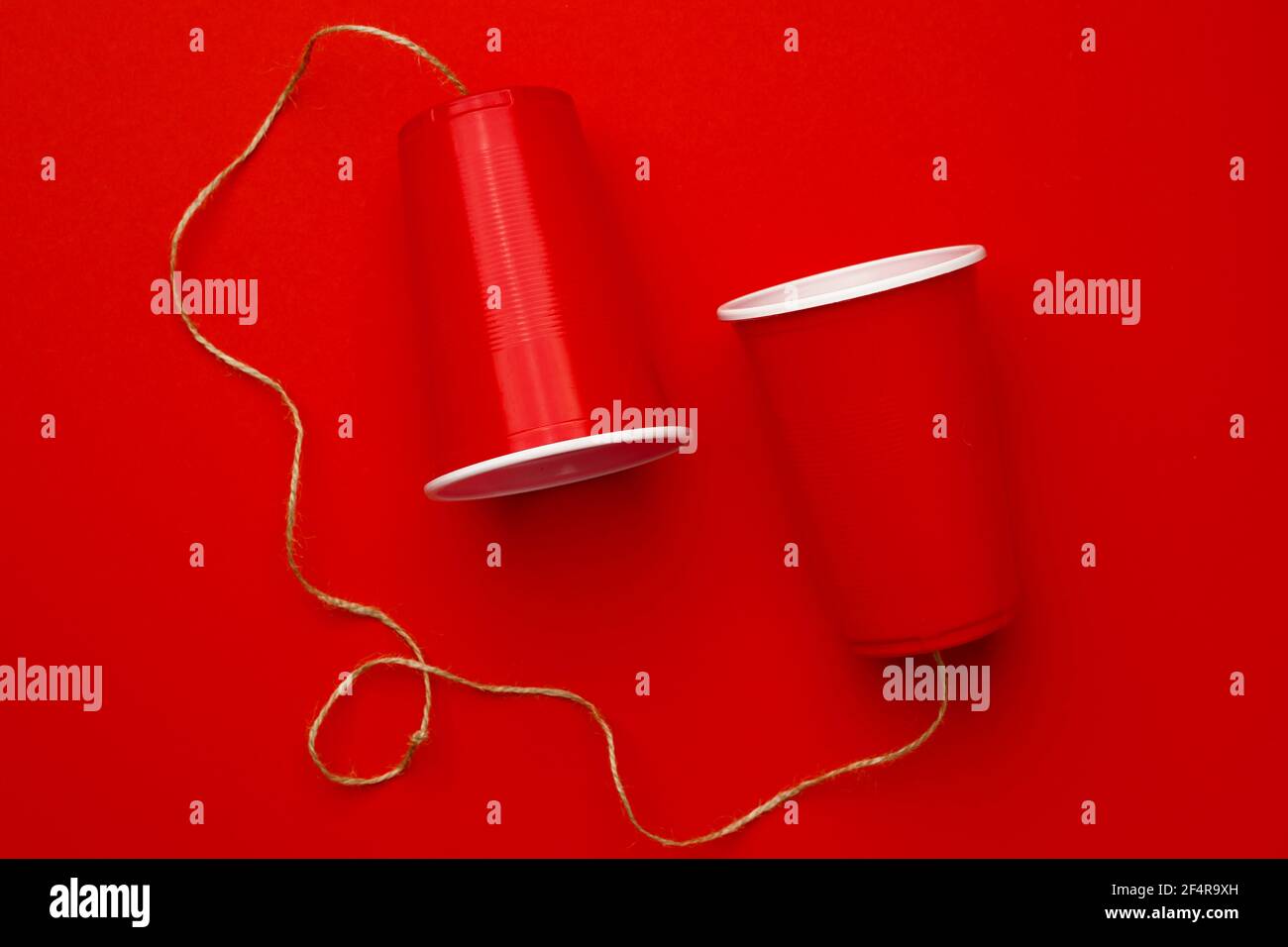 Red plastic cups connected with a thread on red background Stock Photo ...