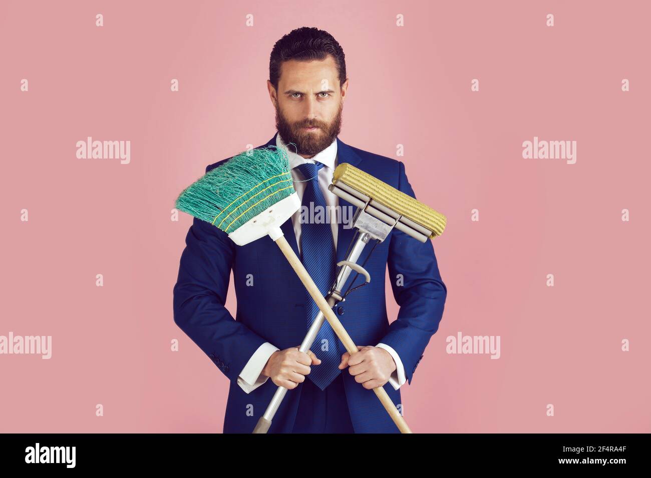 Handsome businessman with cleaning broom on pink background. Business ...