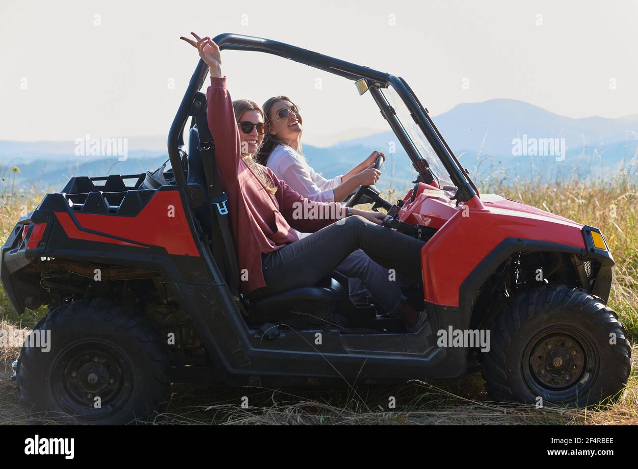 girls enjoying a beautiful sunny day while driving an off-road car ...