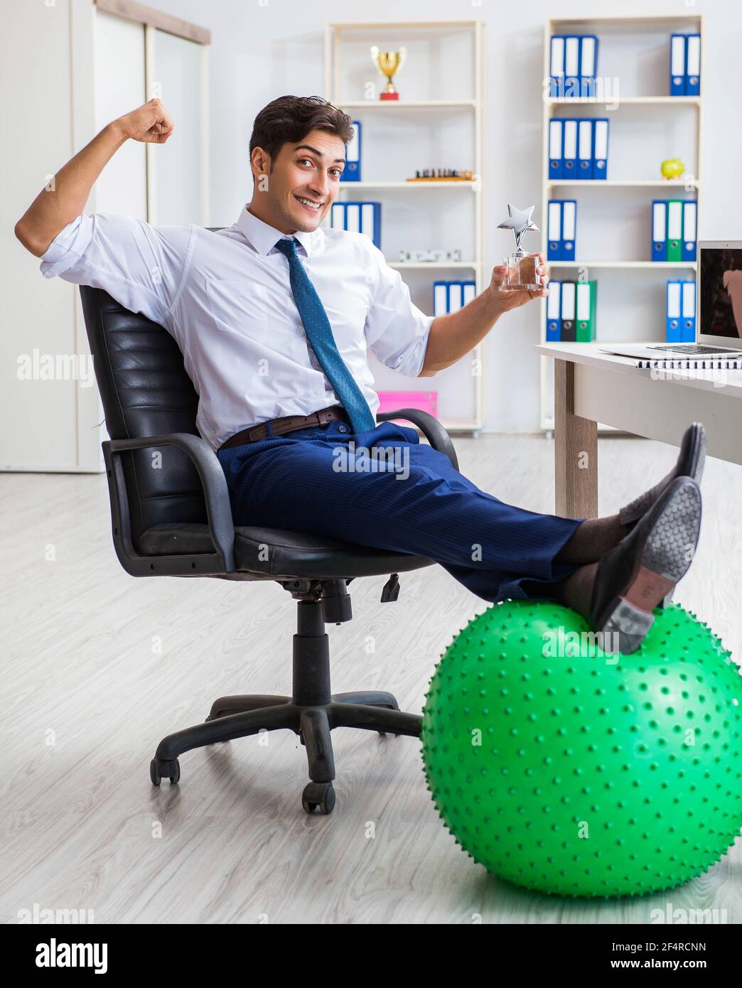 The young businessman doing sports stretching at workplace Stock Photo ...