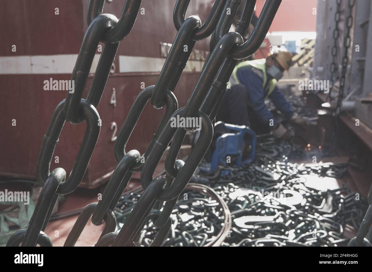 Welder doing welding on deck of ship lashing cargo for sea shipping on ...