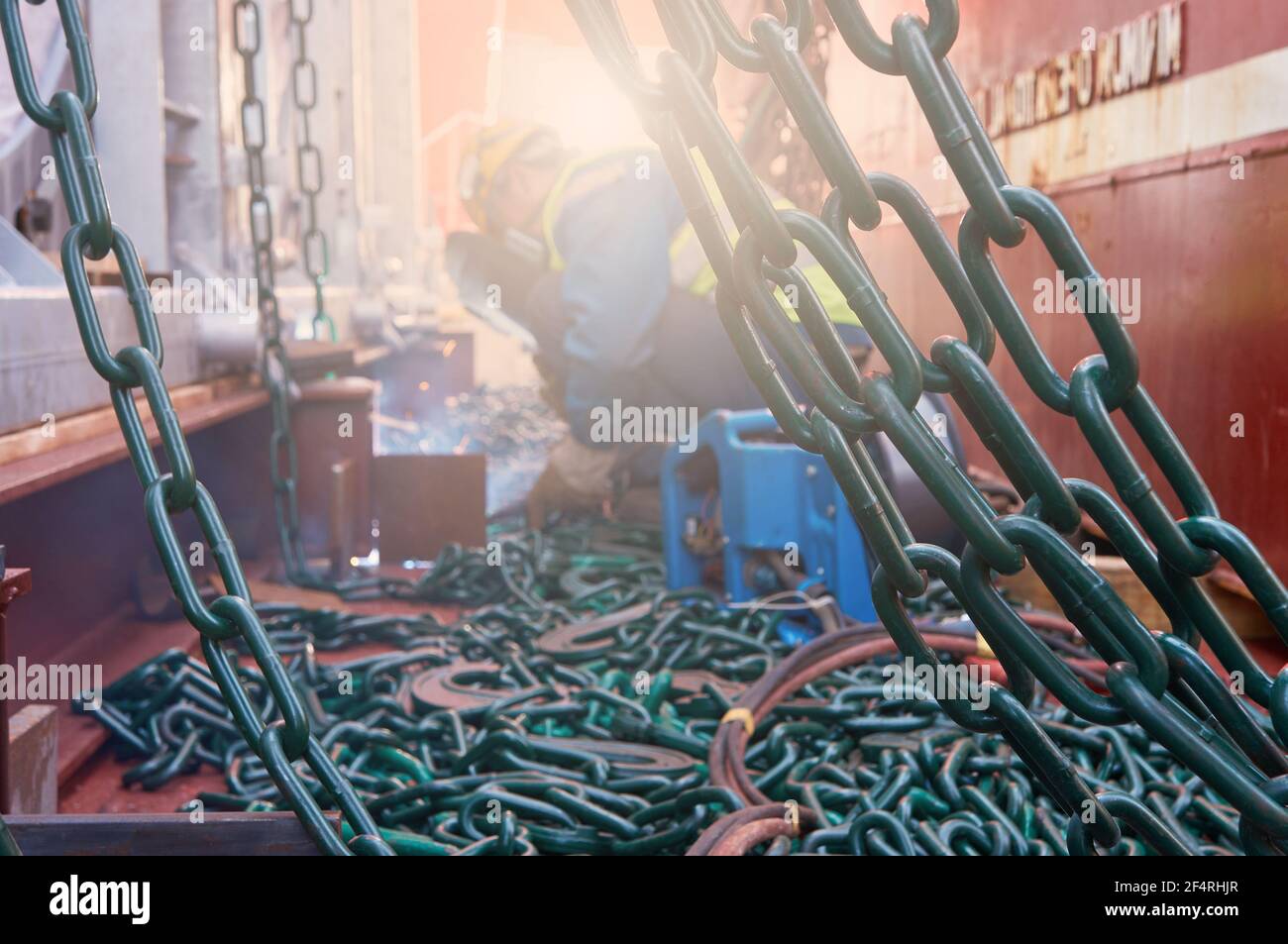 Welder doing welding on deck of ship lashing cargo for sea shipping on background of lenty ...