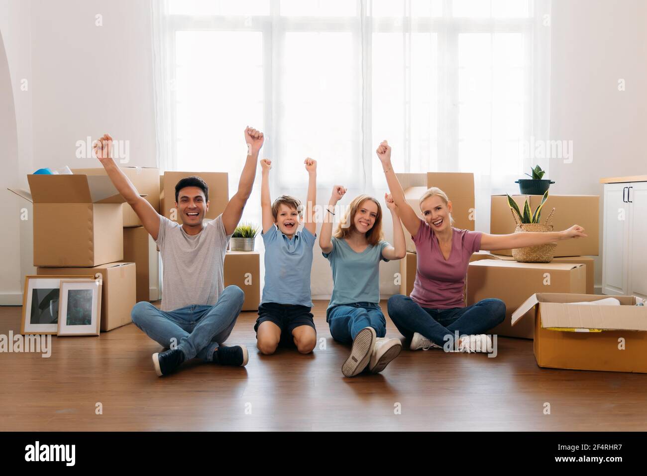 Caucasian Family group of four putting hands up for success in moving ...