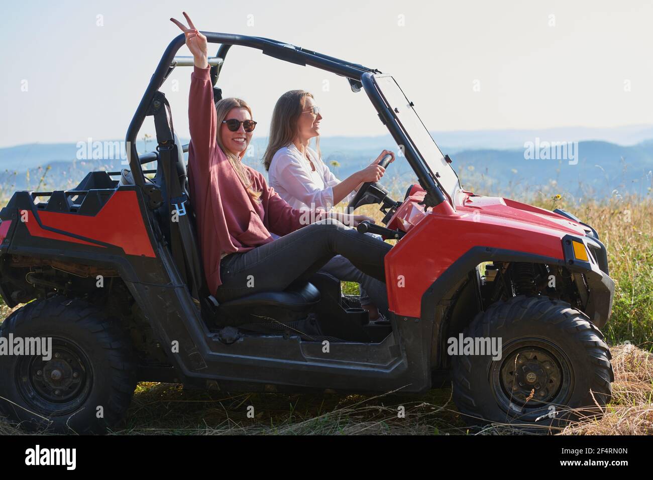 girls enjoying a beautiful sunny day while driving an off-road car ...