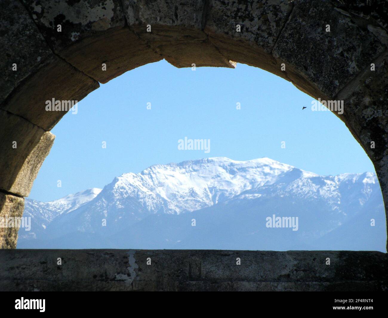 view through an ancient arch to a big snow covered mountain Stock Photo ...