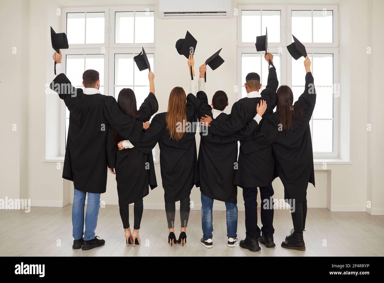 Rear view students stand in a classroom with their backs to the camera ...