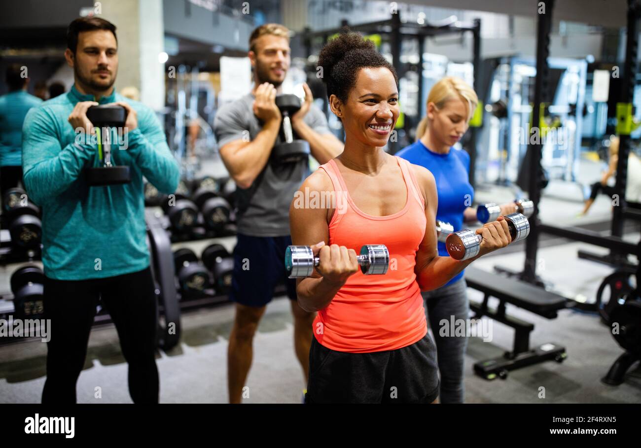 Group of young happy fit people doing exercises in gym Stock Photo - Alamy