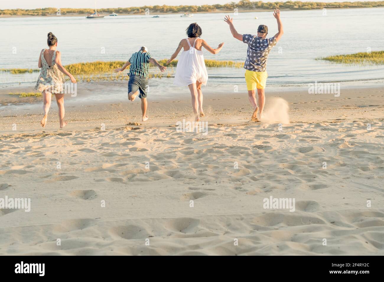 back view of young friends playing and having fun while running and ...