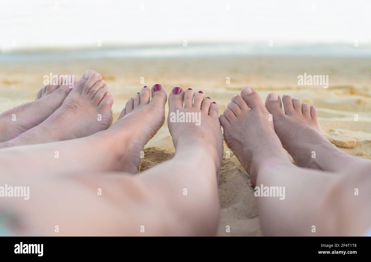 group of friends feet resting and relaxing on the beach with the ocean ...