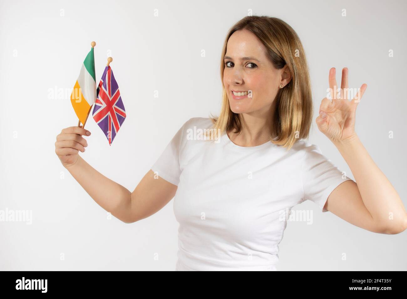 Portrait of a smiling casual young woman holding british and irish ...