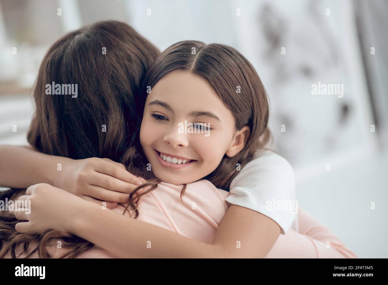 Joyful cute girl hugging long haired mom Stock Photo - Alamy