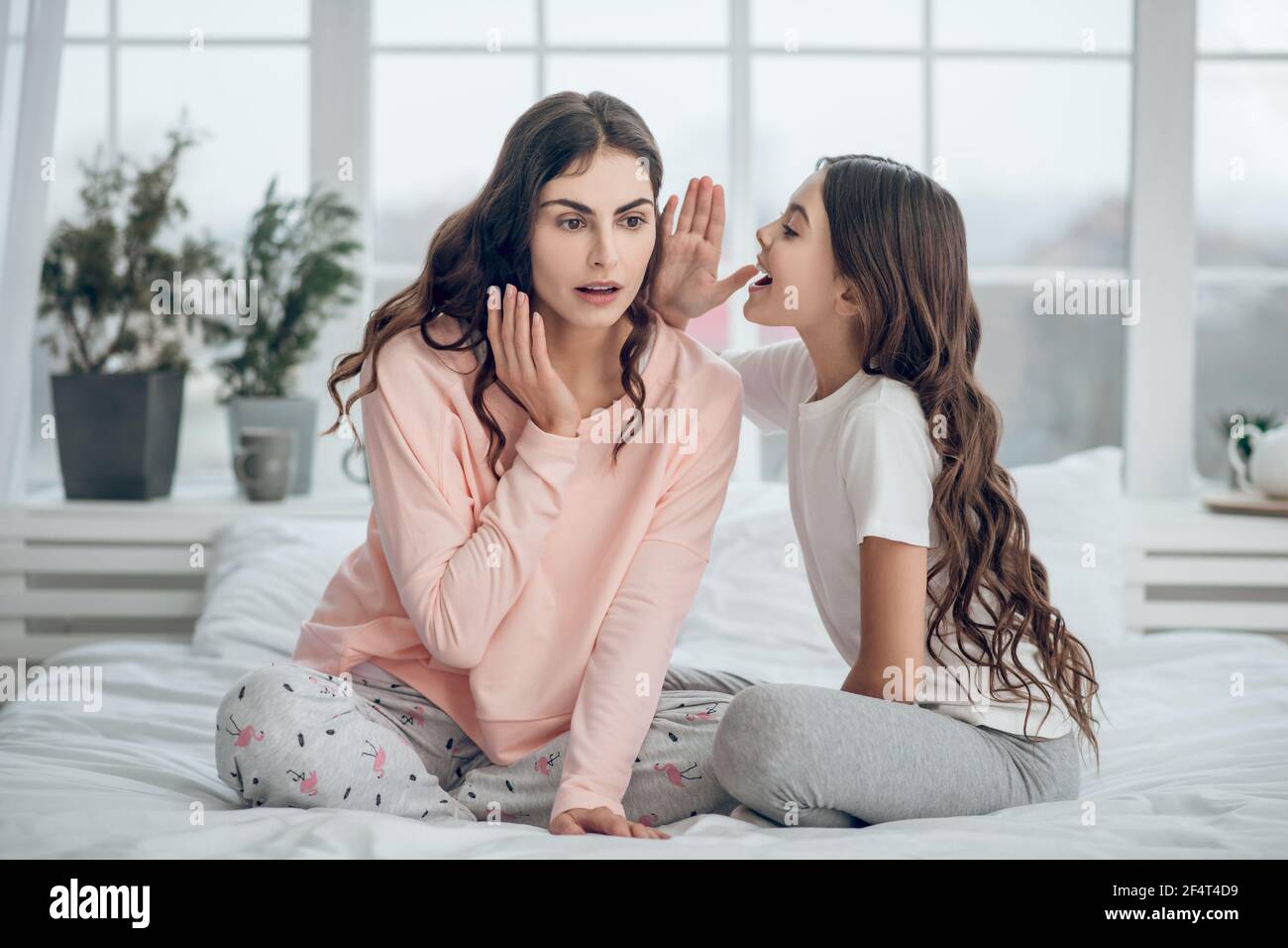 Girl quietly telling secret to mother in ear Stock Photo - Alamy