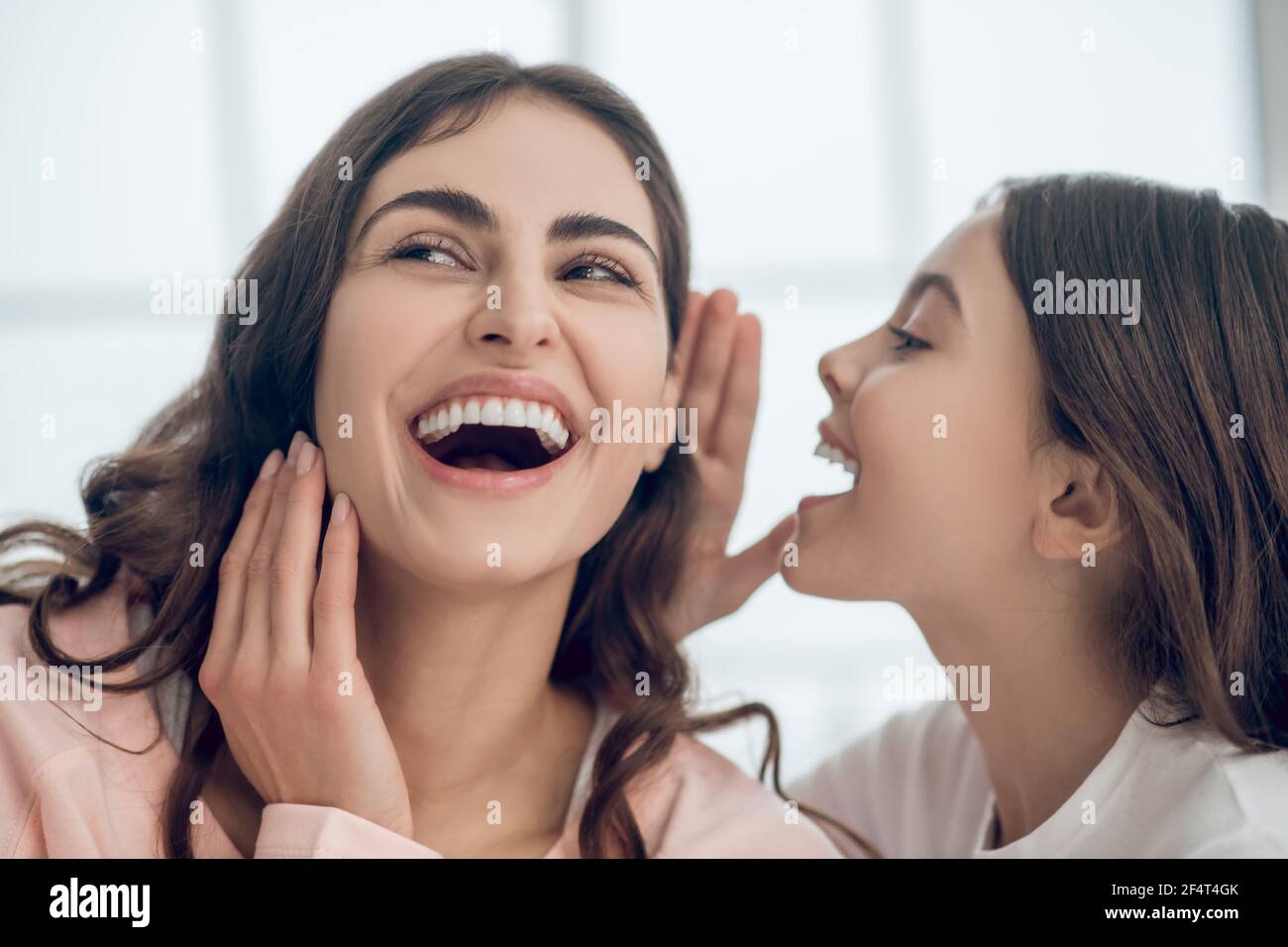 Daughter speaking in ear of laughing mother Stock Photo - Alamy