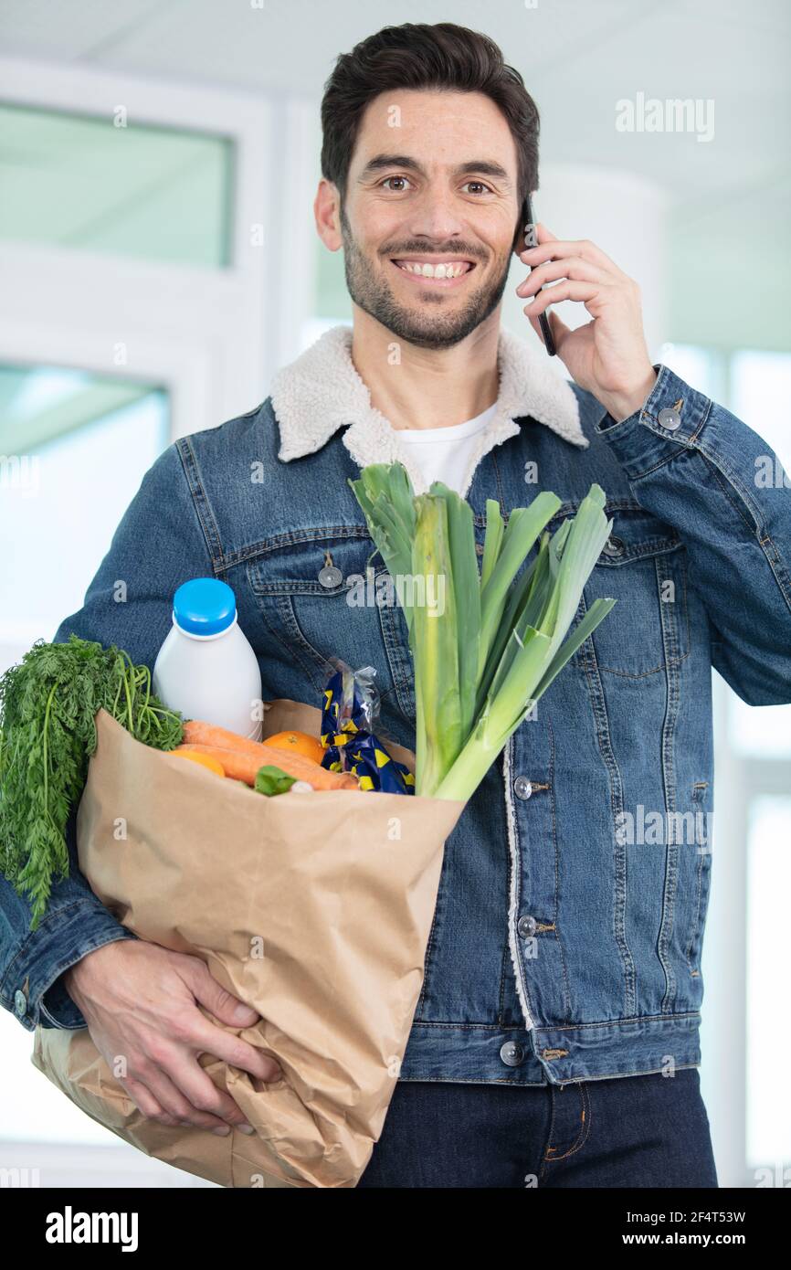 handsome man holding a paper bag full of healthy food Stock Photo - Alamy