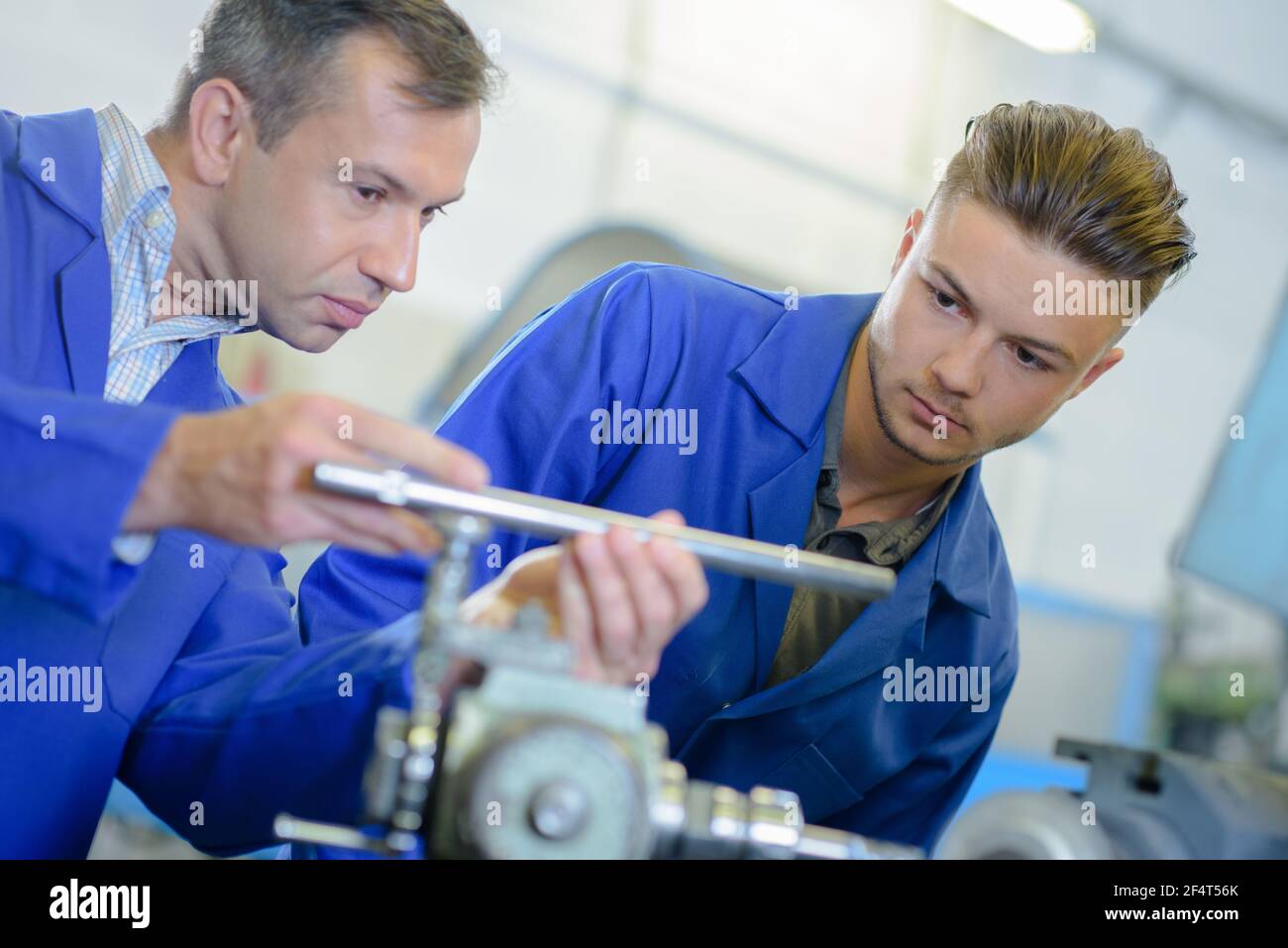 Engineer and trainee looking at metal rod Stock Photo - Alamy