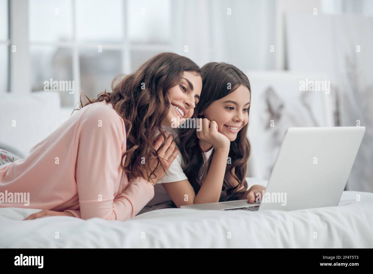 Mom hugging daughter looking into laptop screen Stock Photo - Alamy