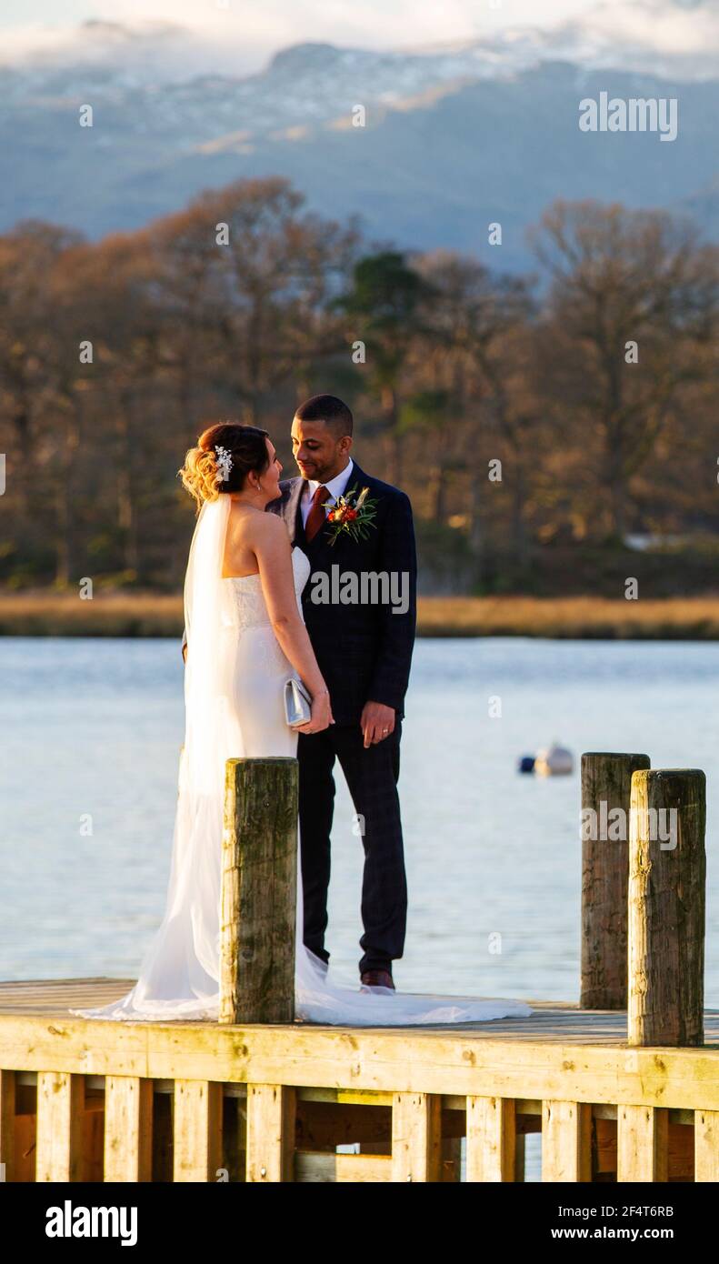 A newly married couple having their wedding photos taken on a jetty at ...