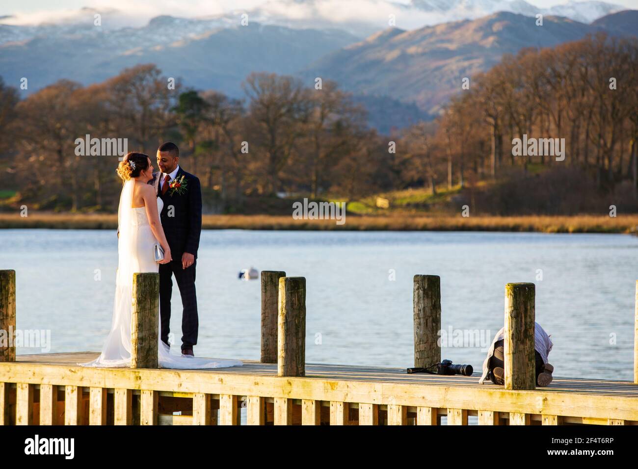 A newly married couple having their wedding photos taken on a jetty at ...