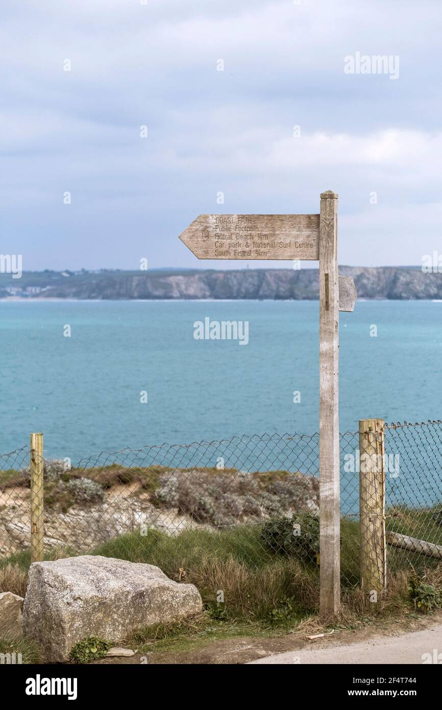 A wooden signpost on the coast path overlooking Newquay Bay in Cornwall ...