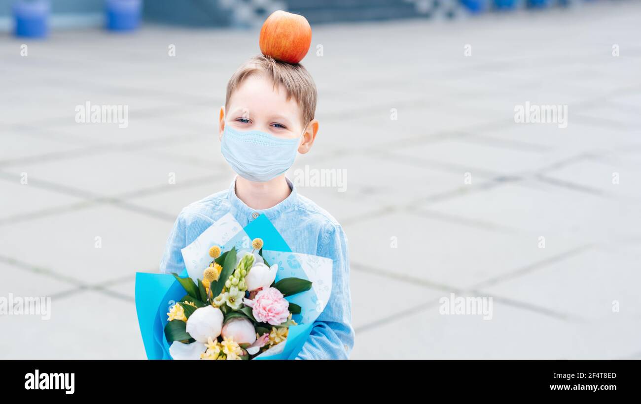 Portrait of schoolboy wearing medicine mask with bouquet in uniform on ...