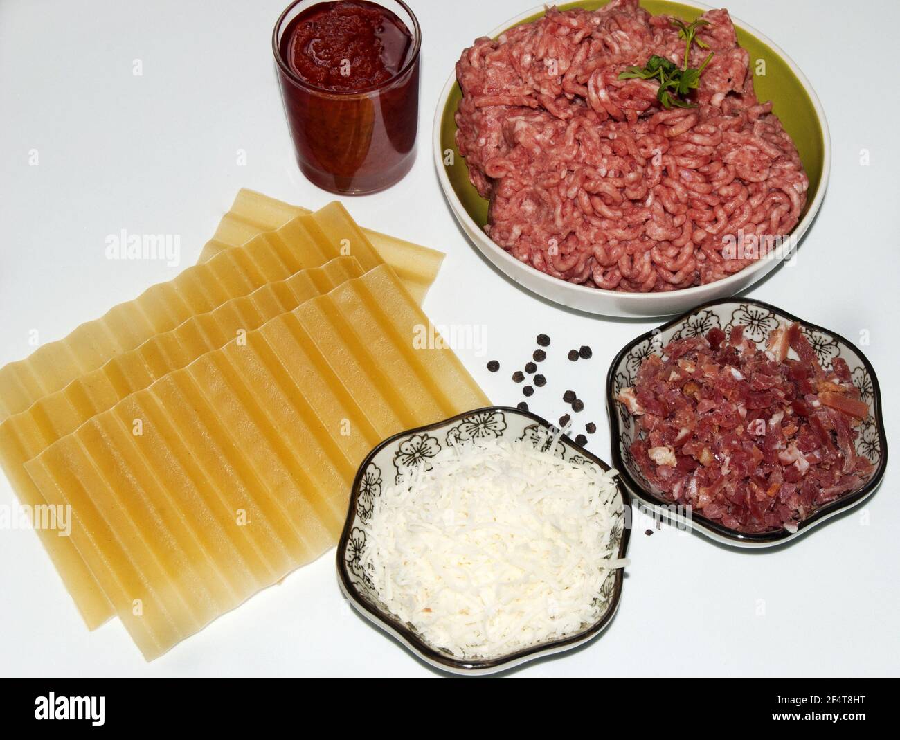 Ingredients for making lasagna: grated, wavy cheese, tomato sauce ...