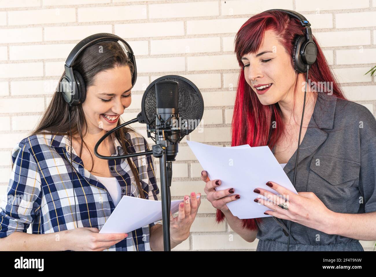Happy young women with scripts smiling and resting near microphone ...