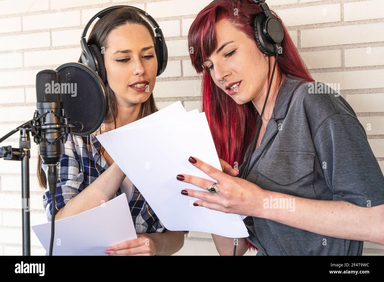 Young women in headphones talking about script while standing near ...