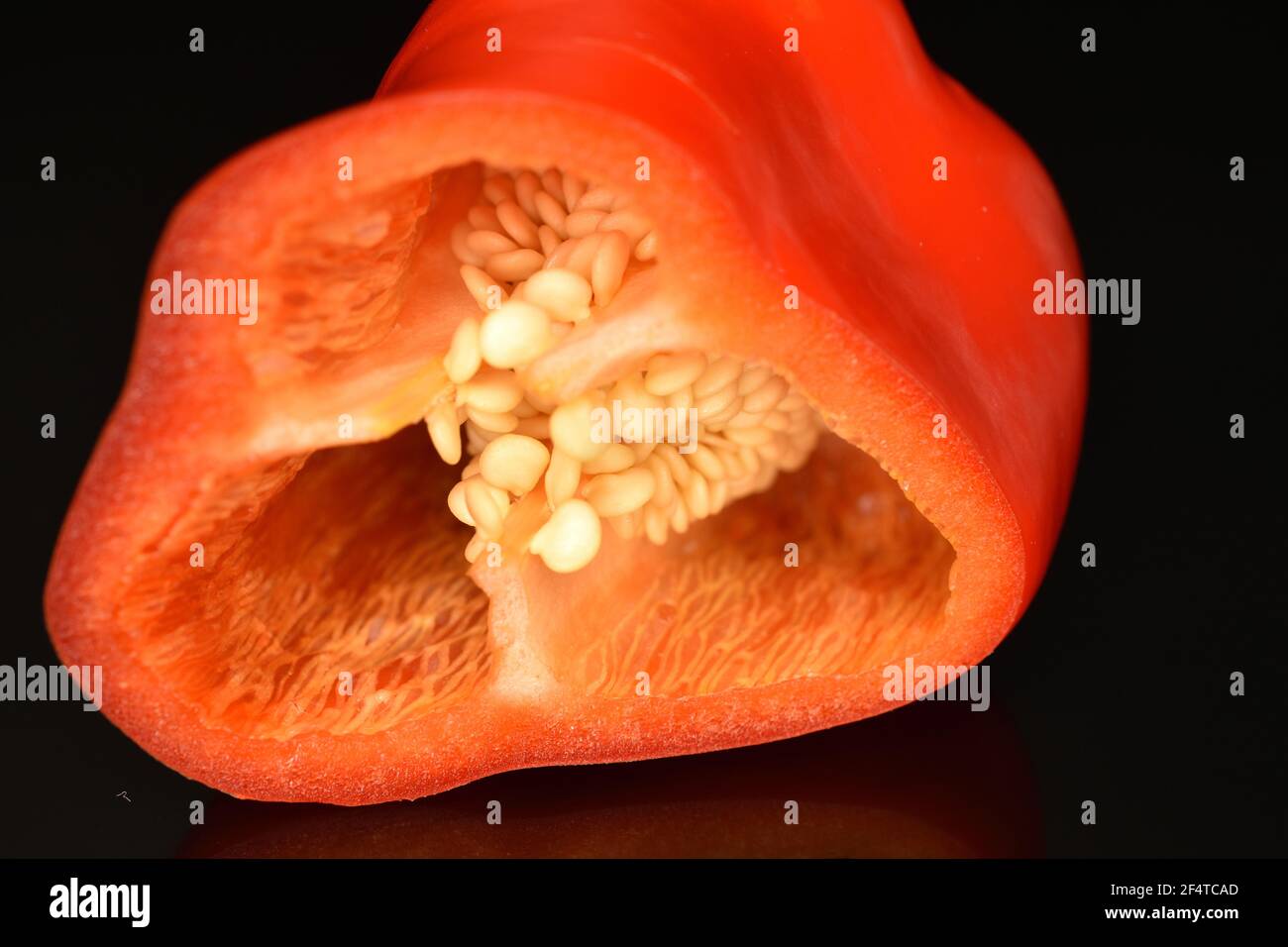 One half of fresh ripe tasty sweet red capia pepper on a black ...