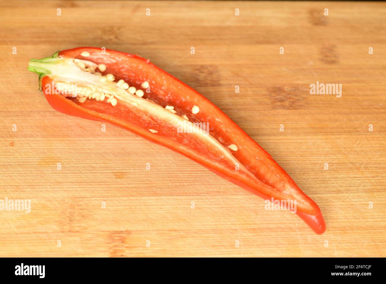 One half of fresh ripe tasty sweet red capia pepper on a bamboo cutting ...