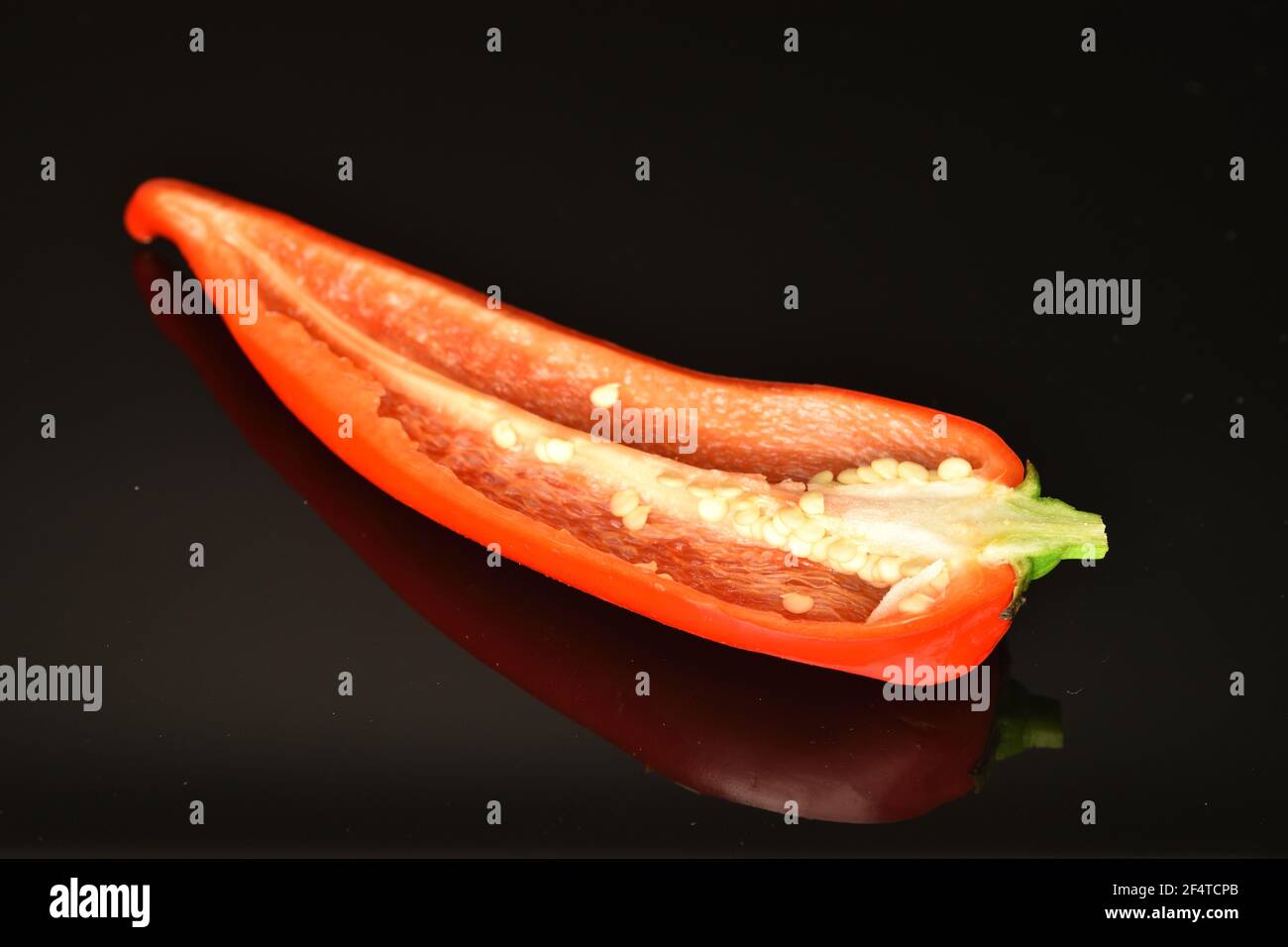 One half of fresh ripe tasty sweet red Kapia pepper on a black ...