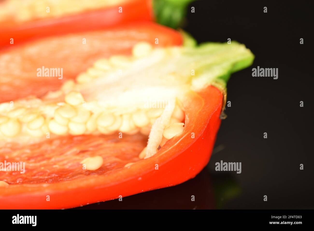 Two halves of fresh ripe tasty sweet red Kapia pepper on a black ...