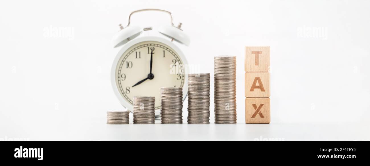 Concept of tax season approaching with wooden blocks, coins and alarm ...