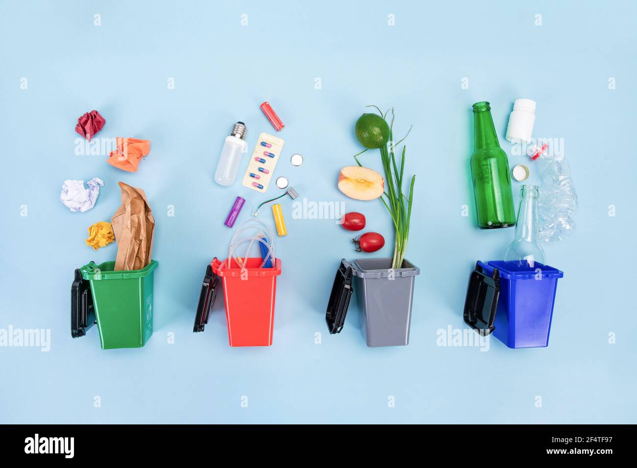 Trash bins with assorted garbage on blue background-the concept of ...