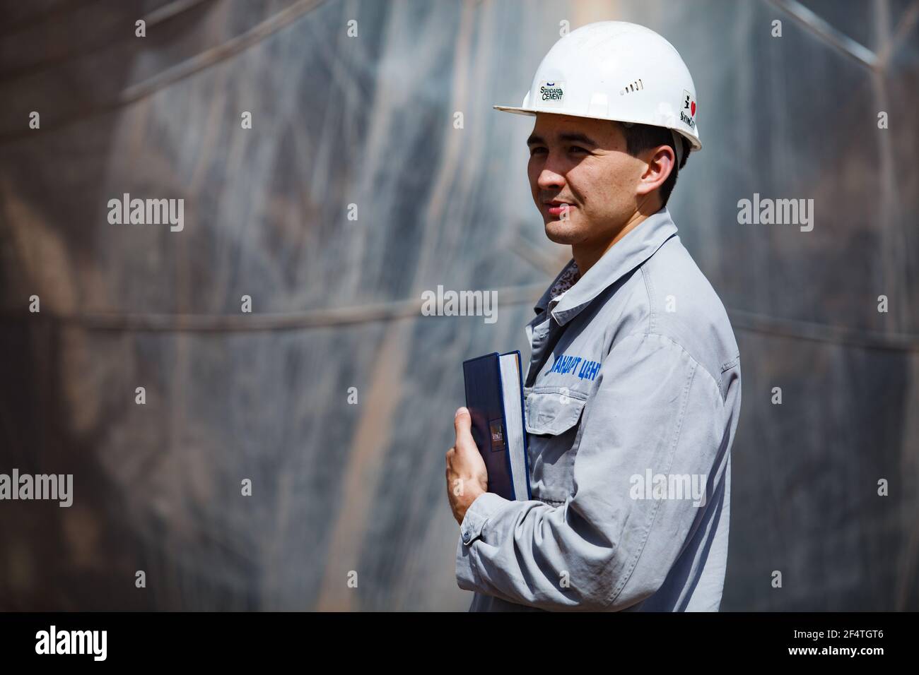 Standard Cement plant. Asian engineer with notebook on shiny metal ...