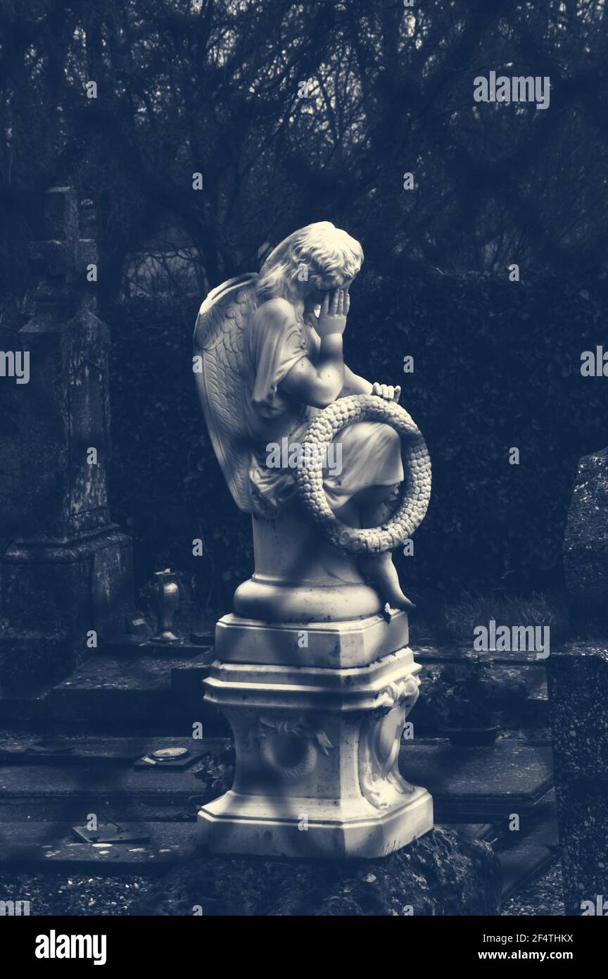 Old cemetery with mourning angel on the tomb holding wreath with word ...
