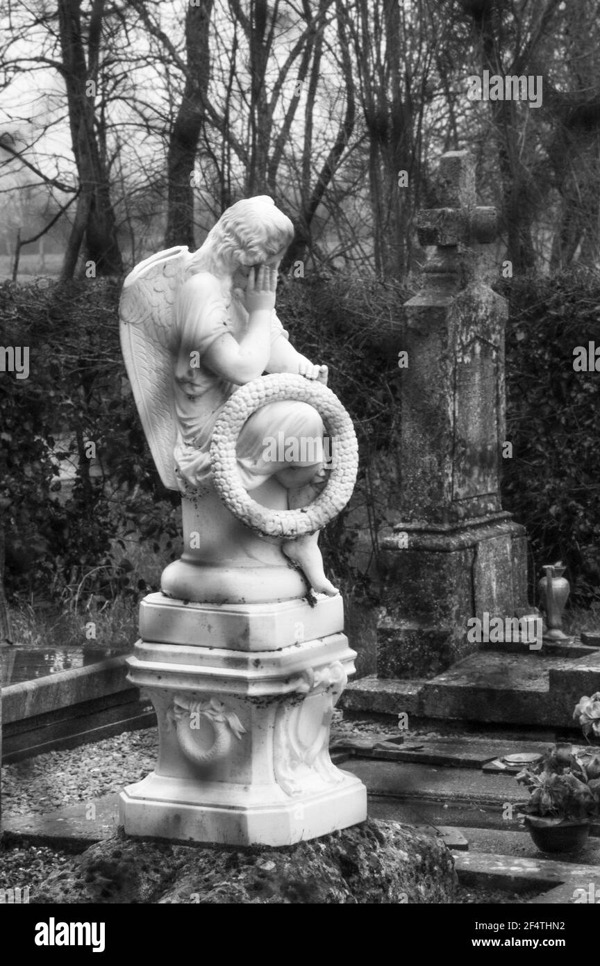 Old cemetery with mourning angel on the tomb holding wreath with word ...