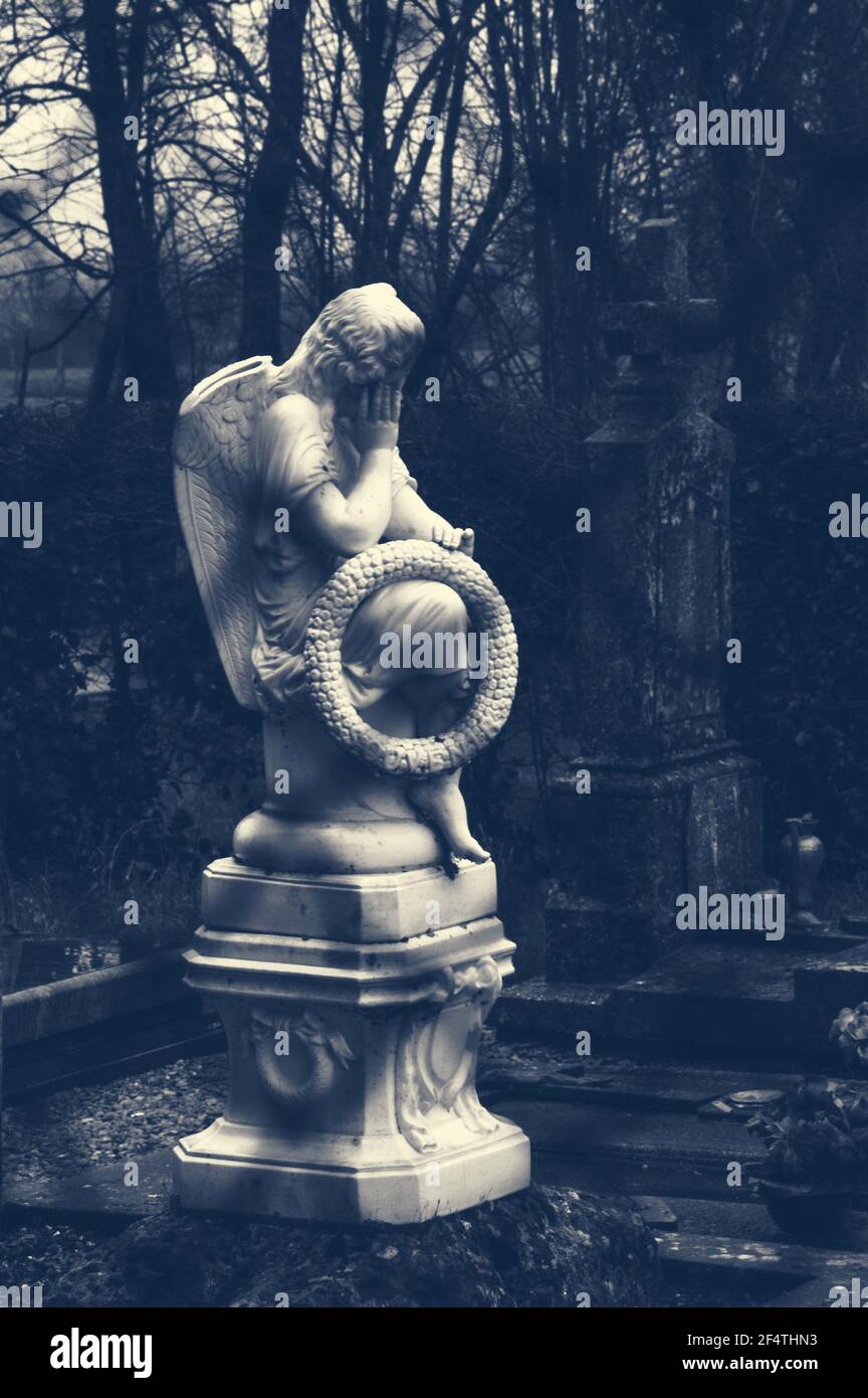 Old cemetery with mourning angel on the tomb holding wreath with word ...