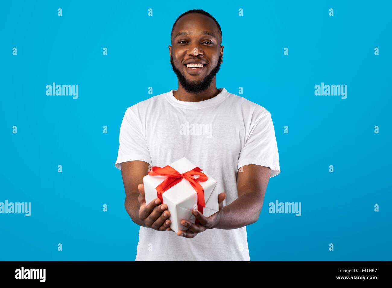Cheerful Black Man Offering Present Box To Camera, Blue Background ...