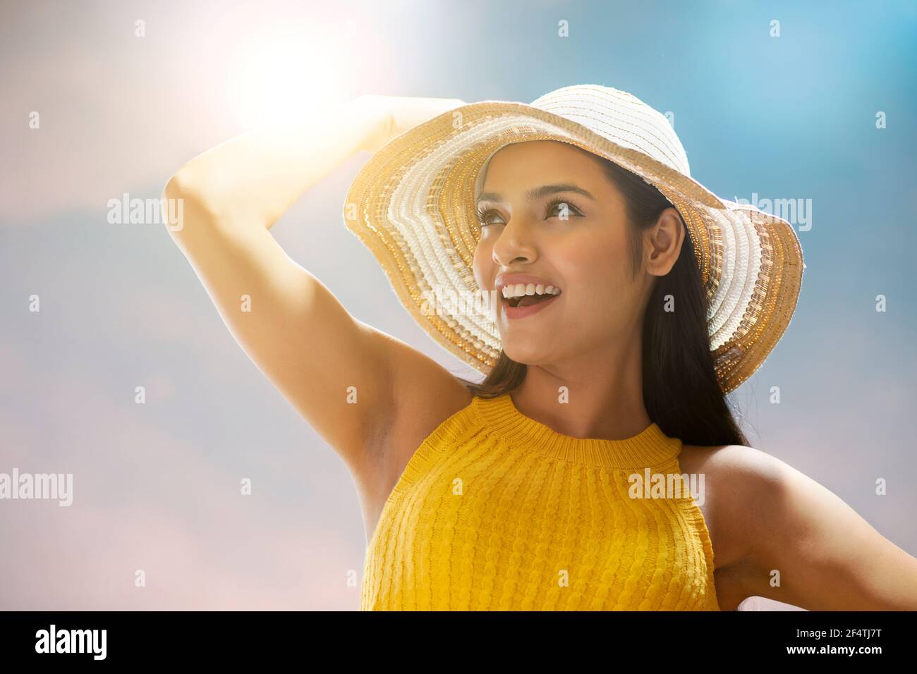 A CONFIDENT YOUNG WOMAN LOOKING ABOVE AND POSING ON A BRIGHT SUNNY DAY ...