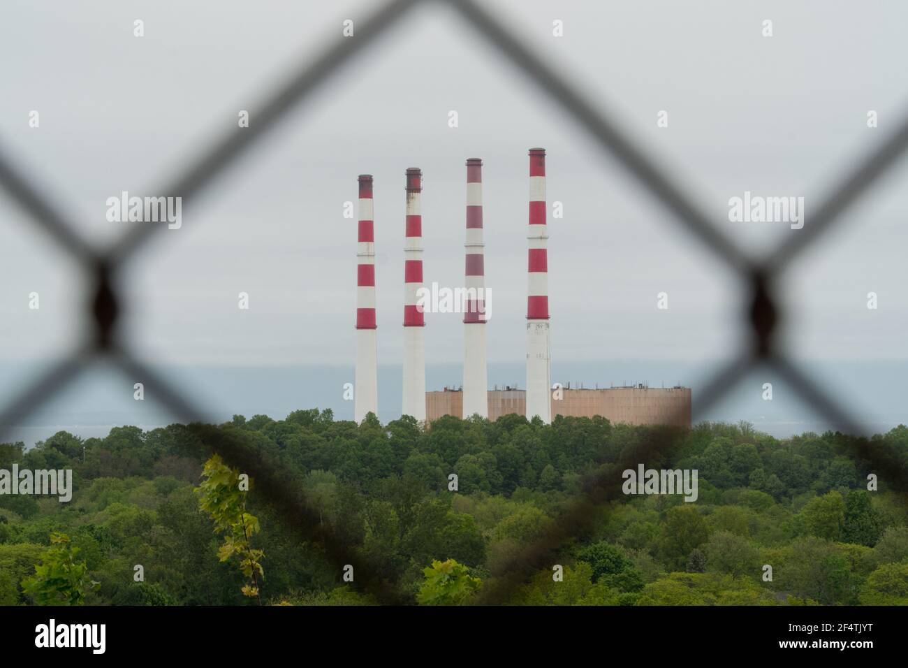 View of tall smoke stacks on power plant through blurry chain link ...